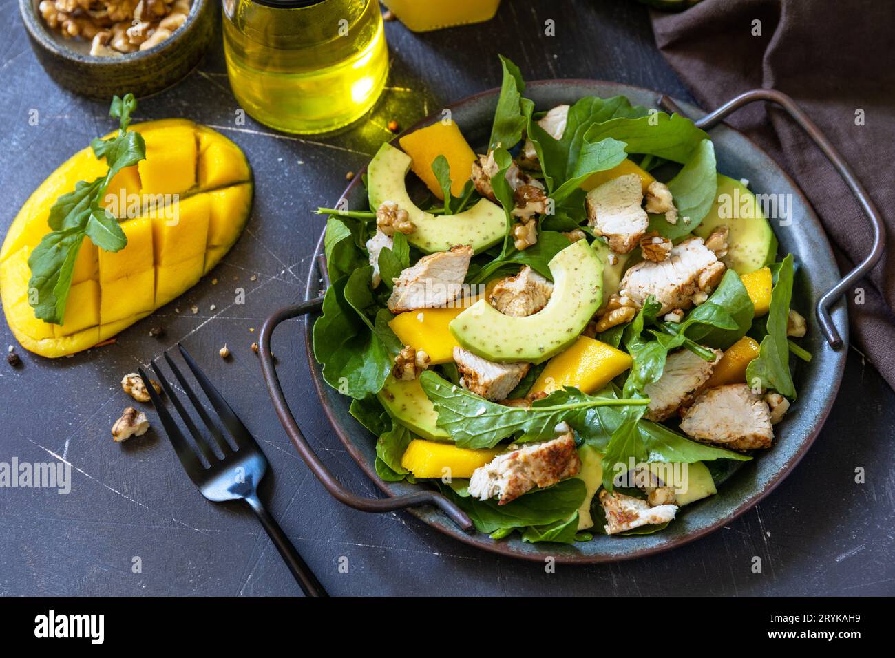 Healthy diet salad with arugula, mango, avocado, chicken grill, walnuts and vinaigrette dressing ...