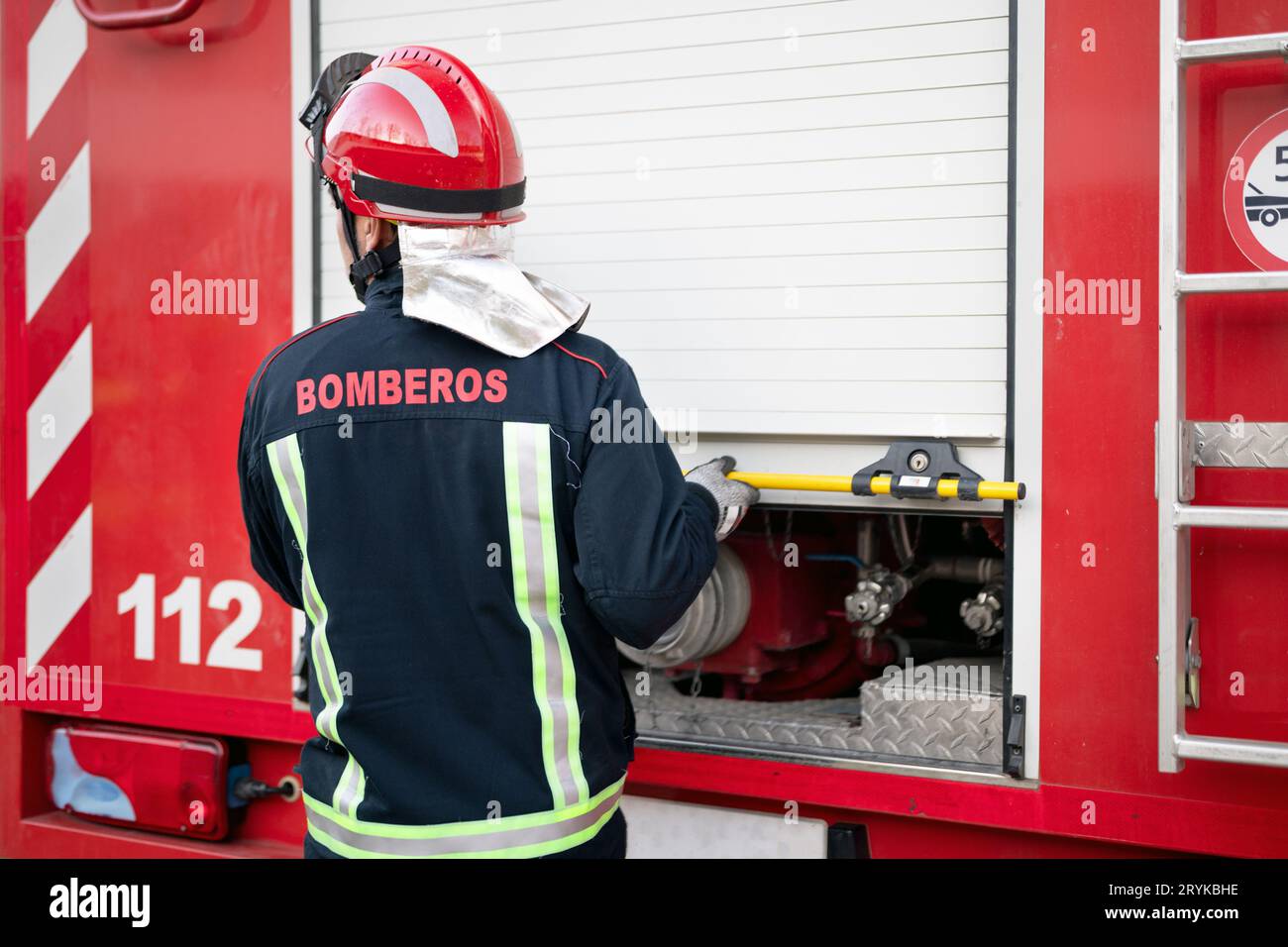 Firefighter in uniform and protective helmet, opening storage cabinet ...