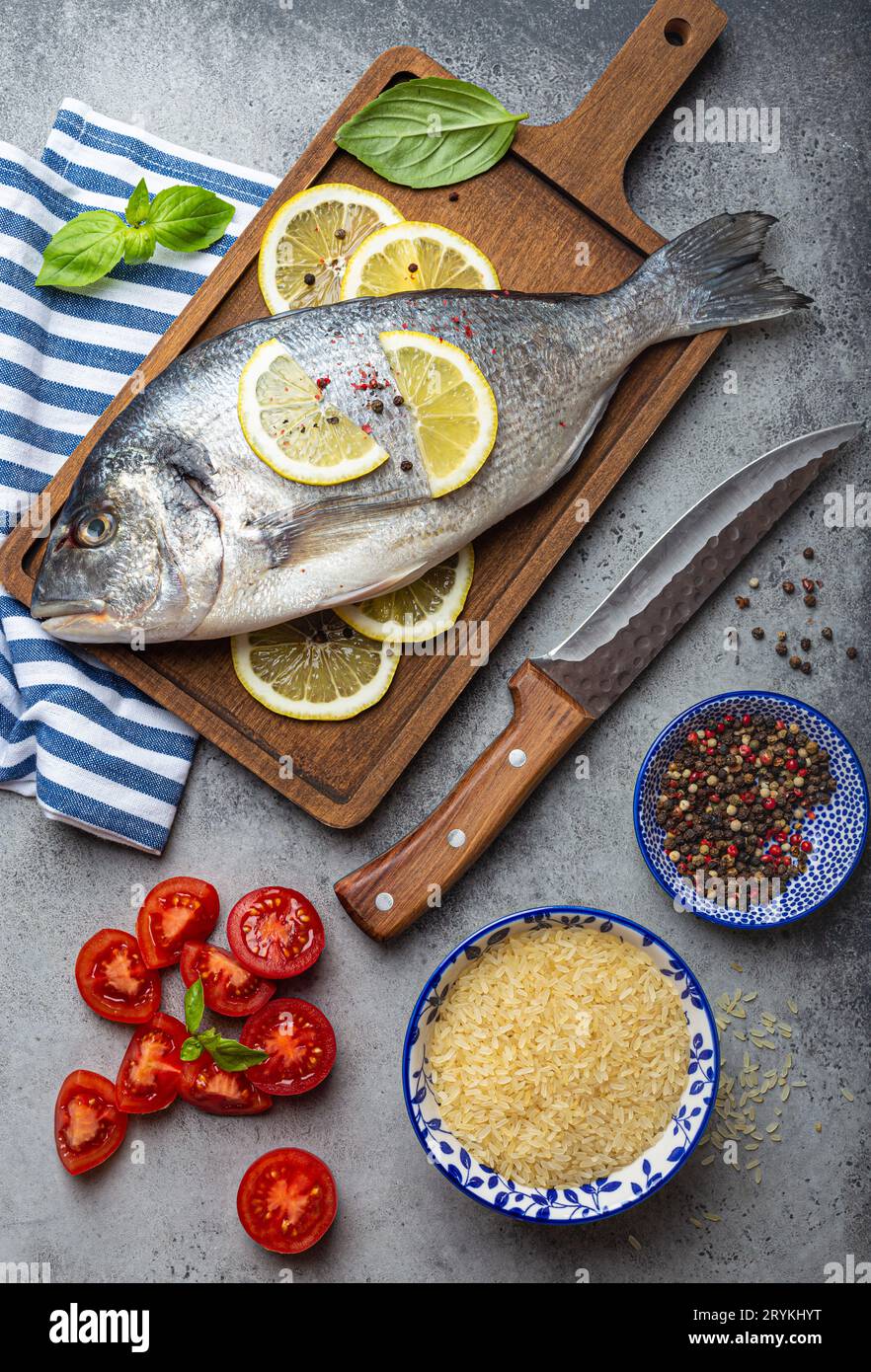 Raw fish dorado with ingredients lemon, fresh basil, cut cherry ...