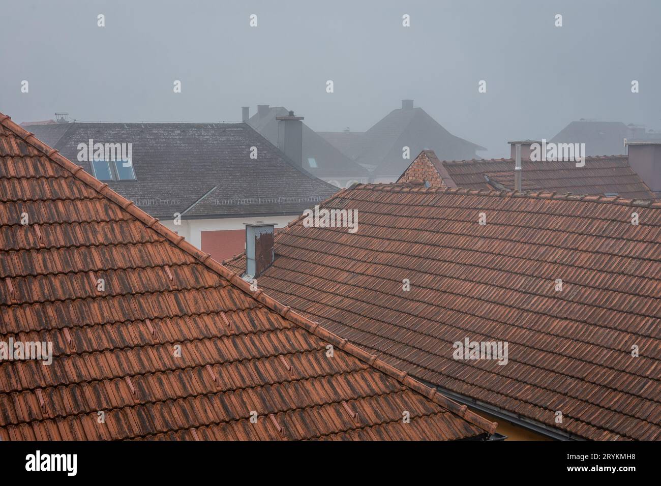 Foggy rooftops, red roof of buildings visible fading into a distant ...