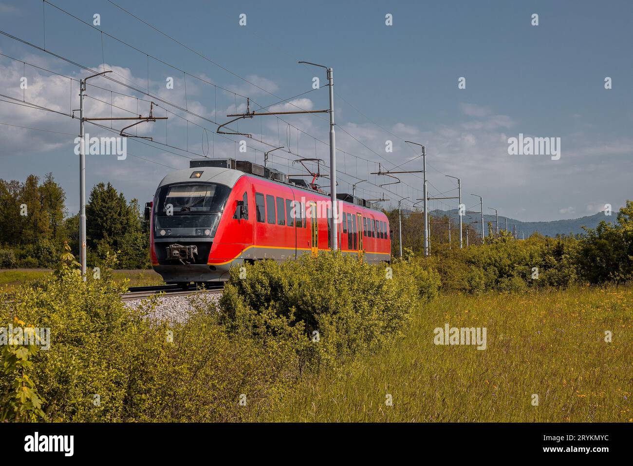 Red electric train unit under modern catenary or cable overhead rail on ...