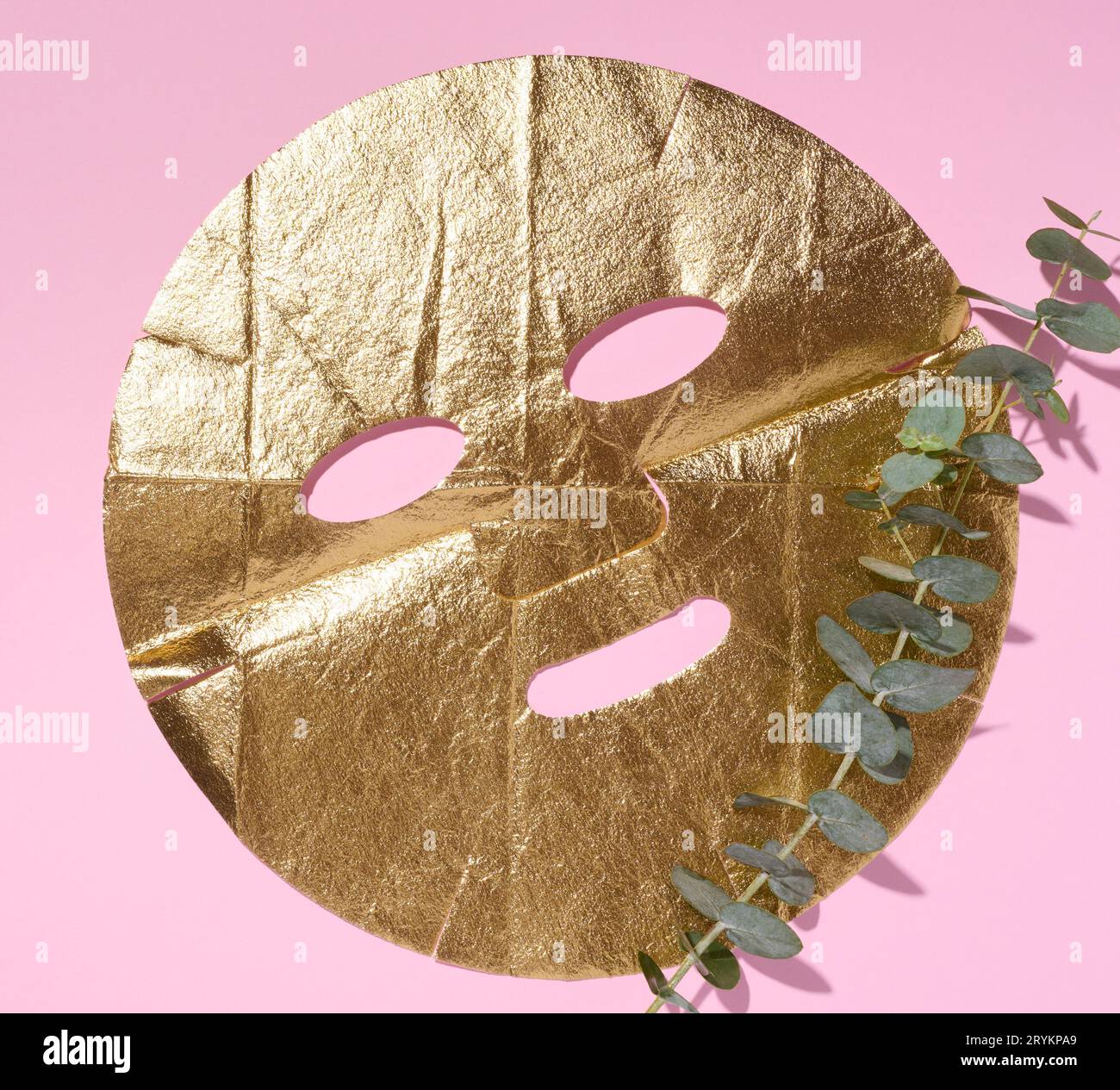 Textile cosmetic mask with gold for the face on a pink background, top ...