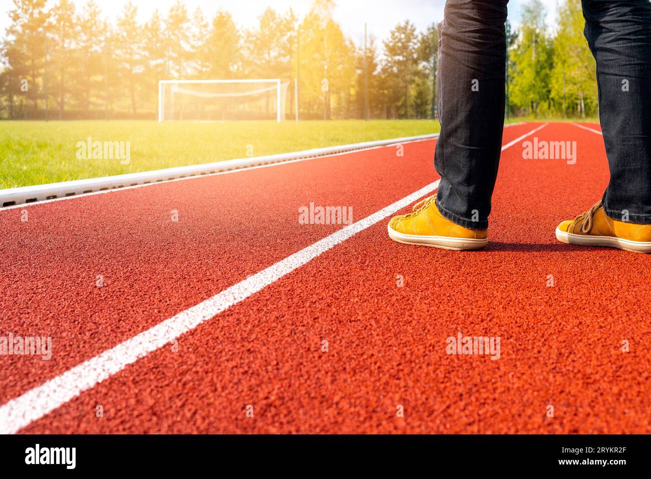 Man standing on the empty stadium with football gate and running track ...
