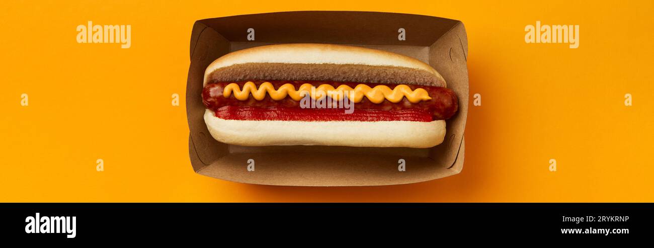 Classic hot dog with wurst, ketchup and mustard on orange background ...