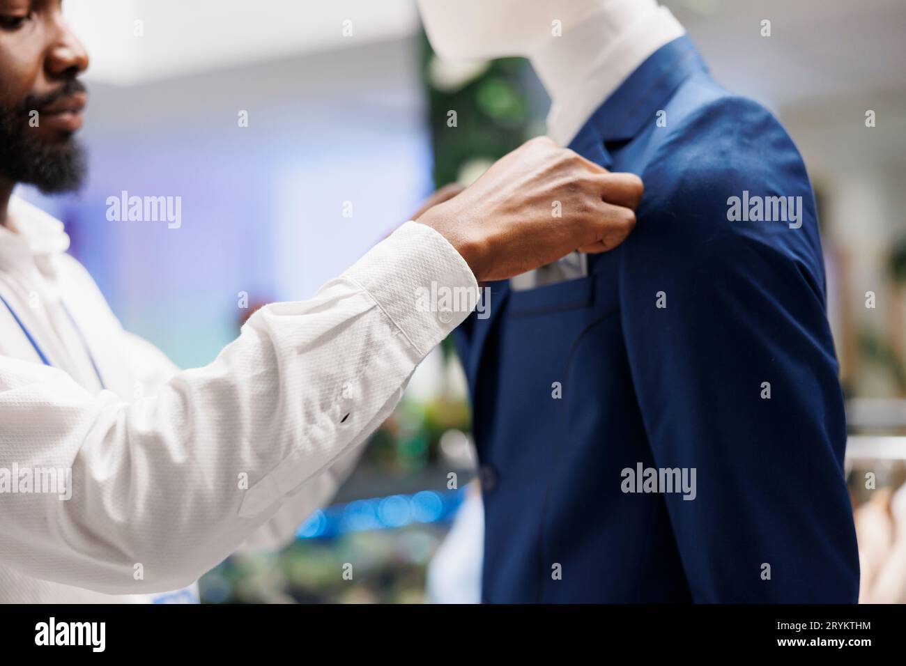 Clothing store assistant hands fastening jacket on mannequin to ...