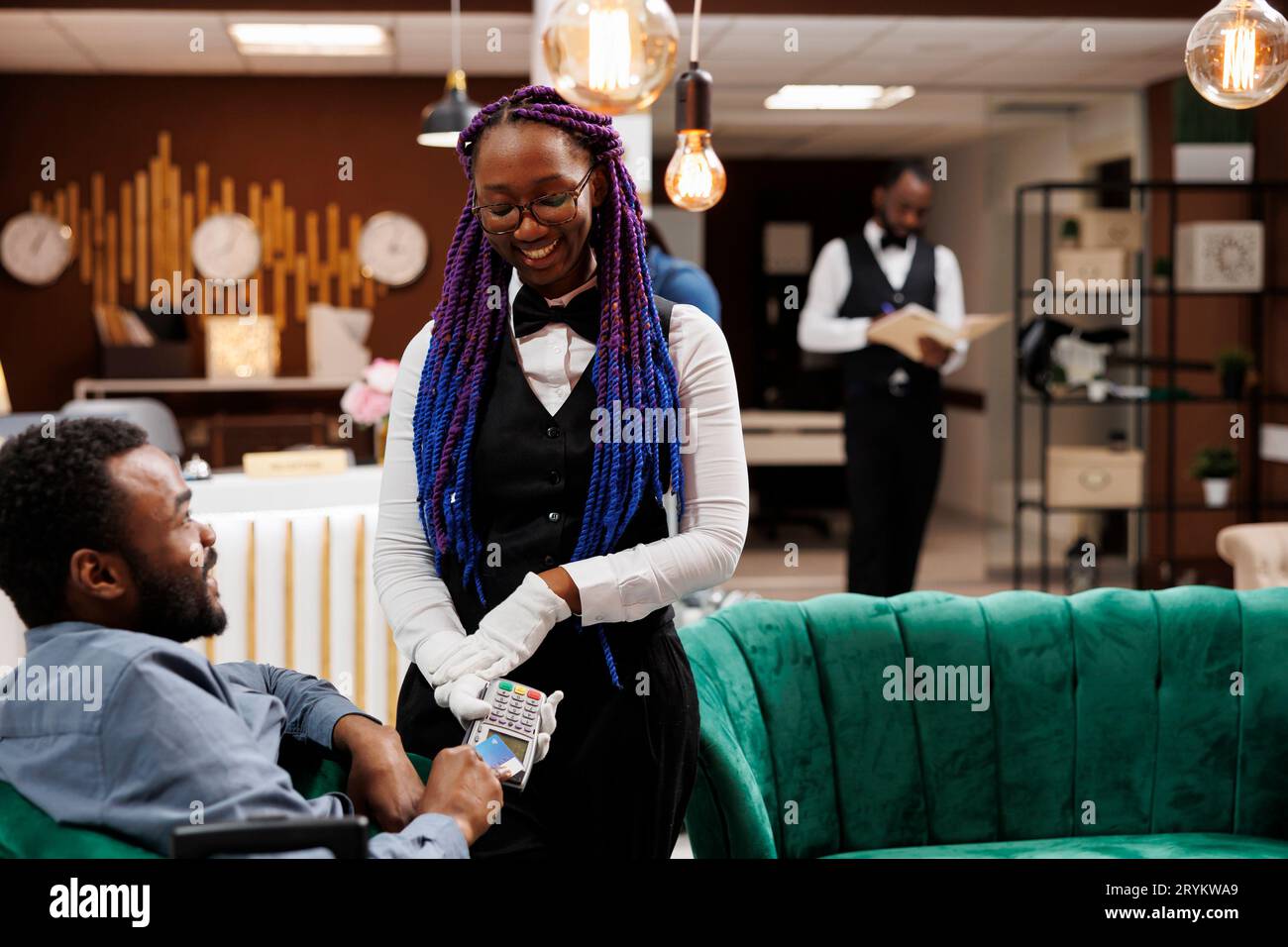 Smiling pleasant African American woman waitress holding POS terminal ...