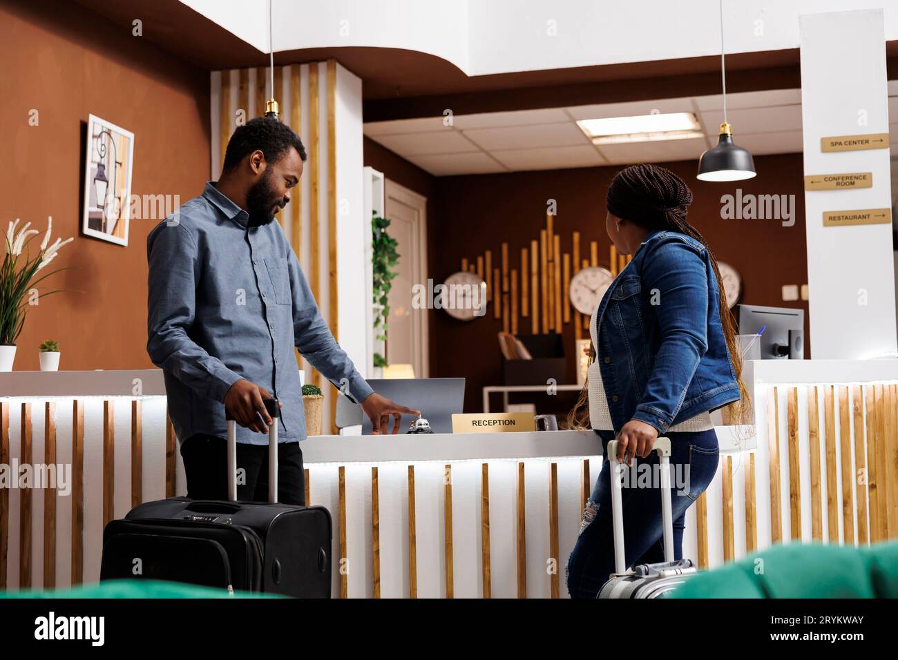 African American family couple standing with luggage at empty reception ...