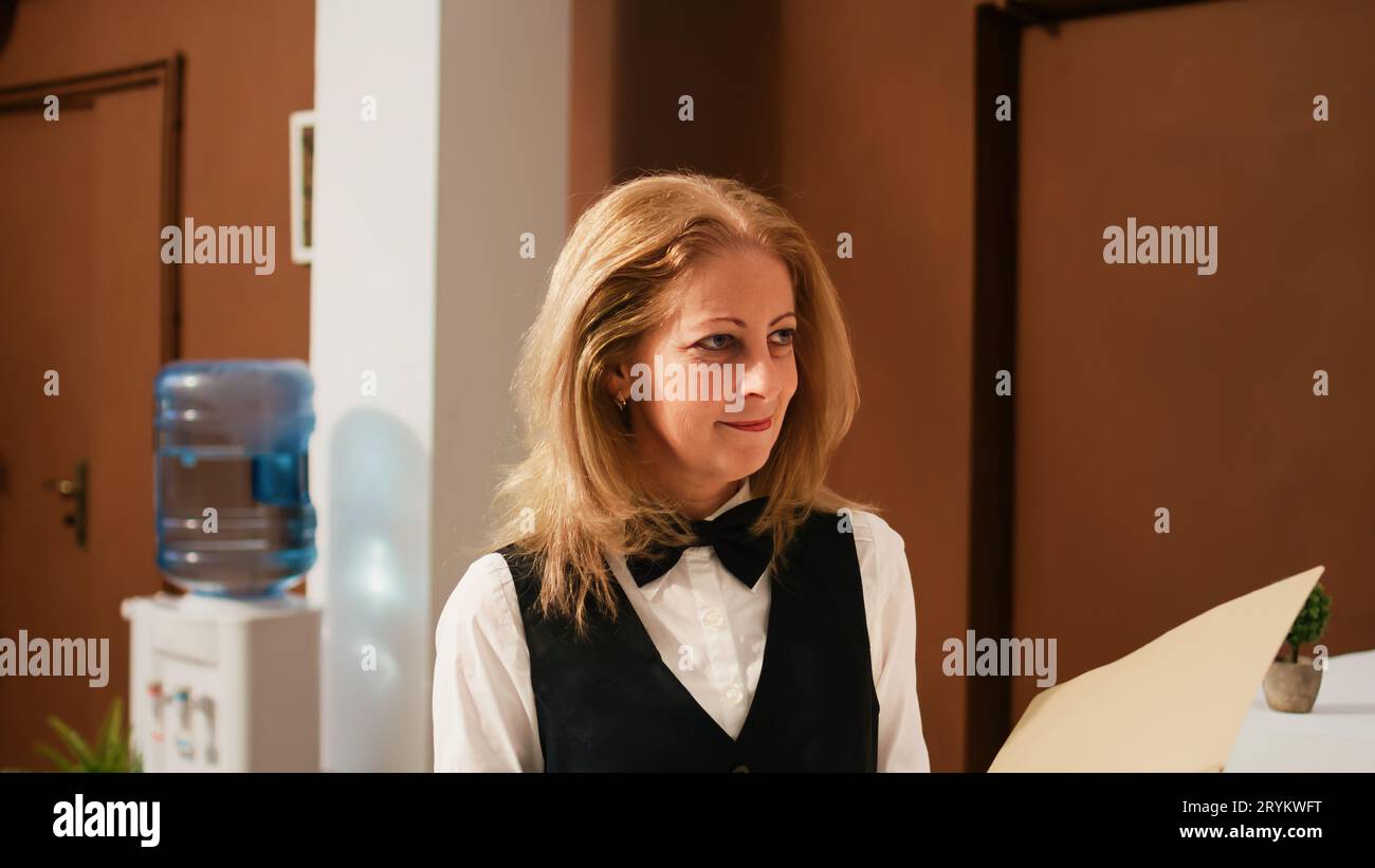 Hotel employee with check in documents reviewing room availability at ...