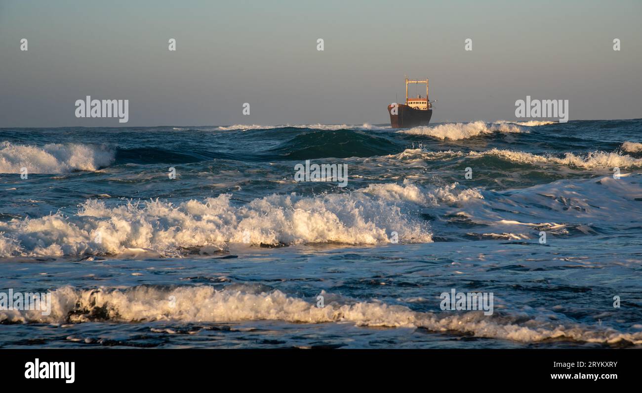 Abandoned ship in the stormy sea with big wind waves at sunset ...