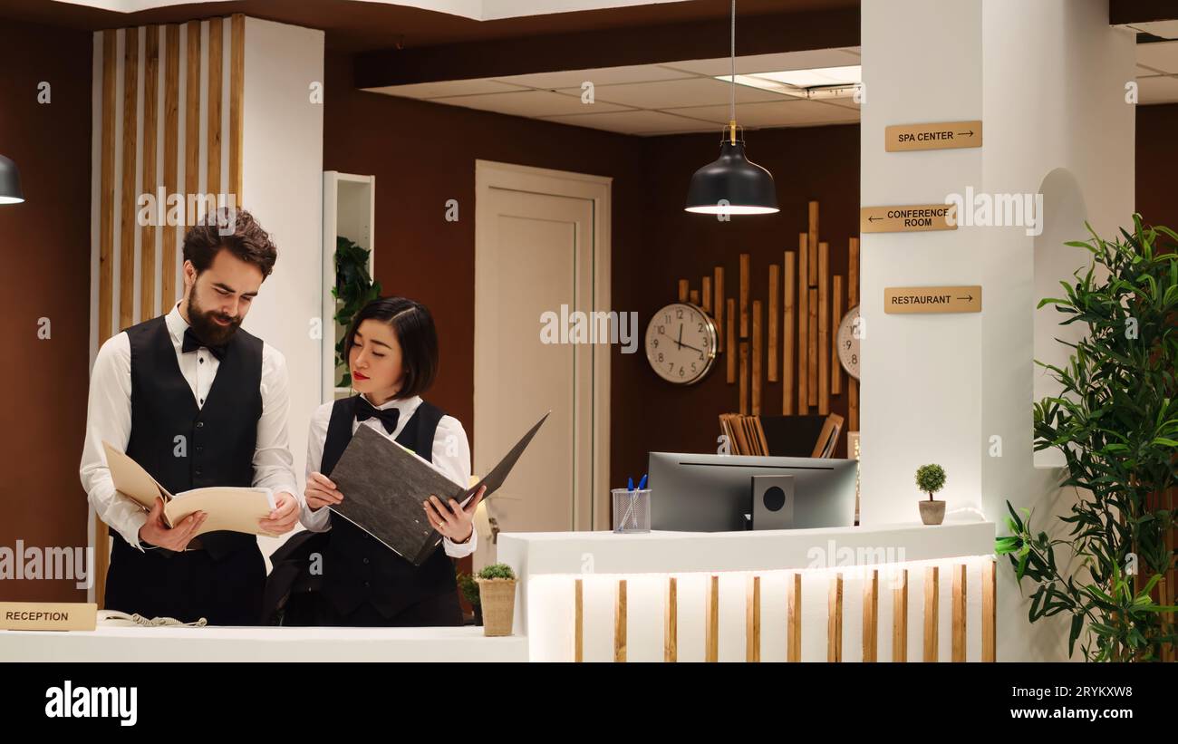 Happy receptionists cross referencing tourists booking appointment data ...