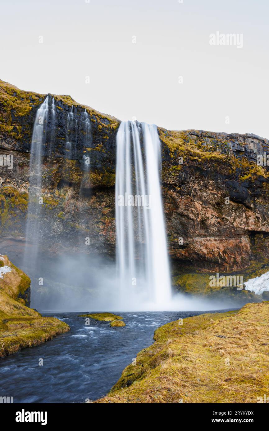 Picturesque icelandic cascade surrounded by high mountains and ...