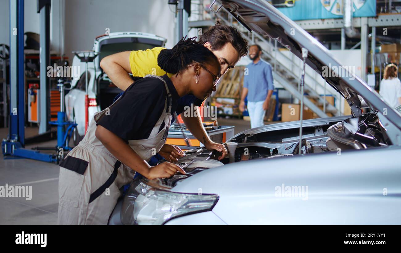 Repair shop employees using torque wrench and pliers to fix car in need ...