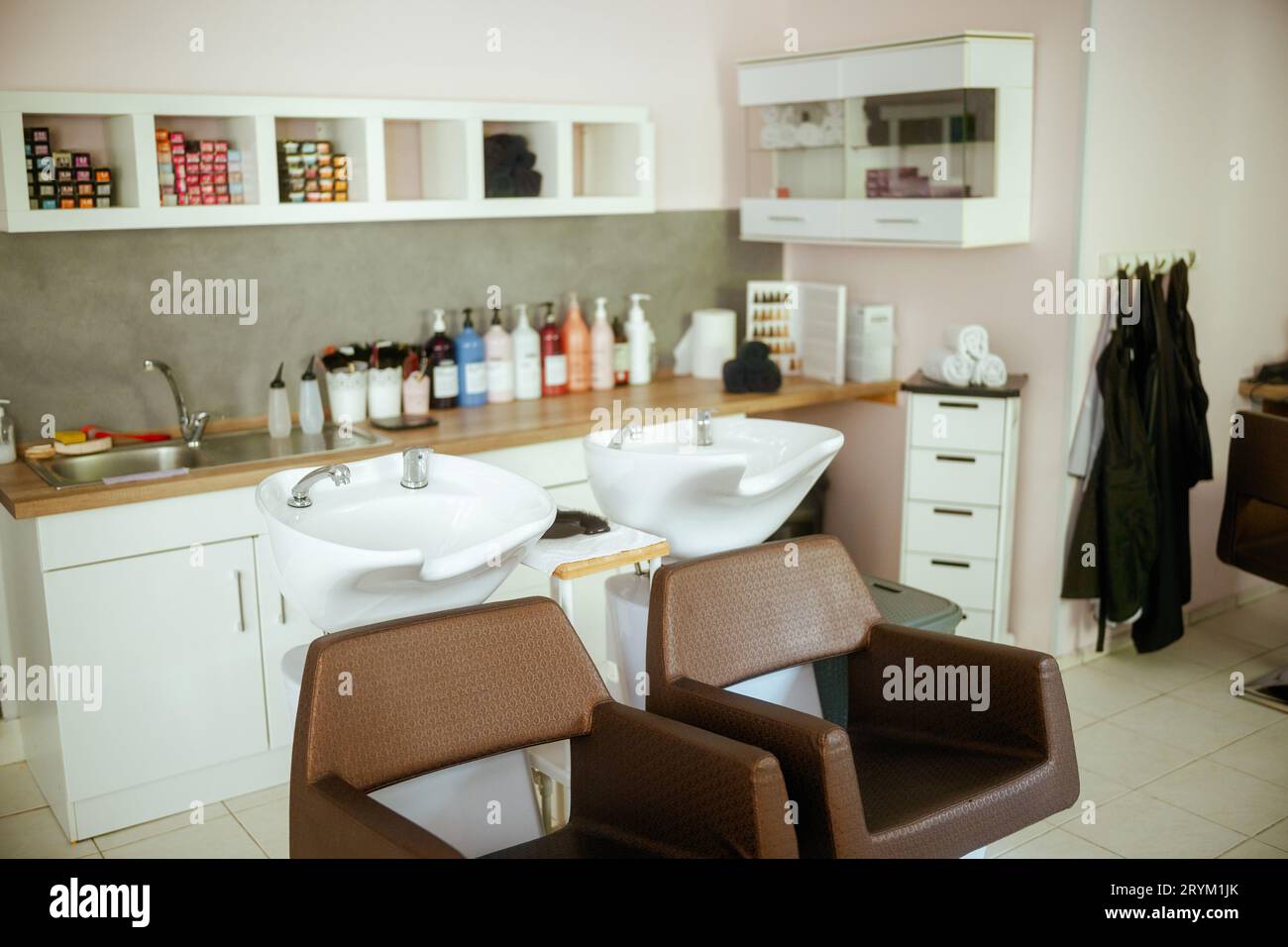 modern beauty salon with chairs, bottles of hair care products and ...