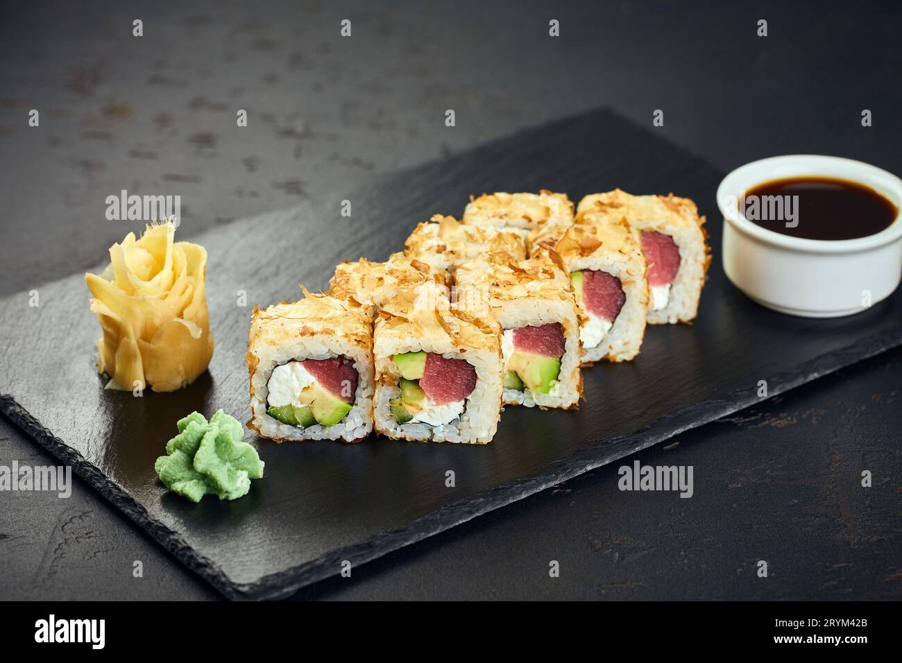 Sushi roll with tuna, avocado, cream cheese and tuna shavings on dark ...