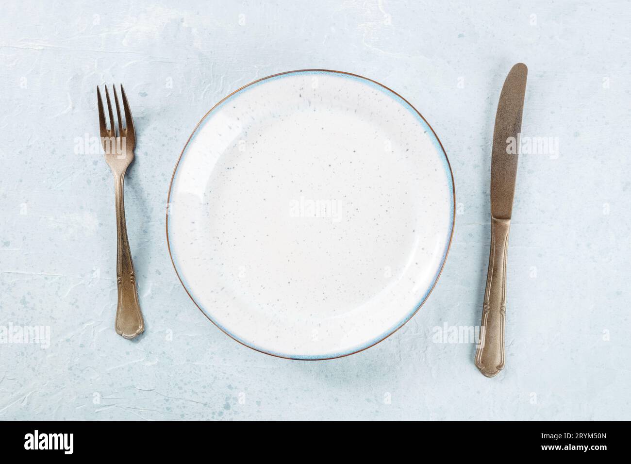 An empty white plate with a blue rim, with a fork and a knife, overhead ...