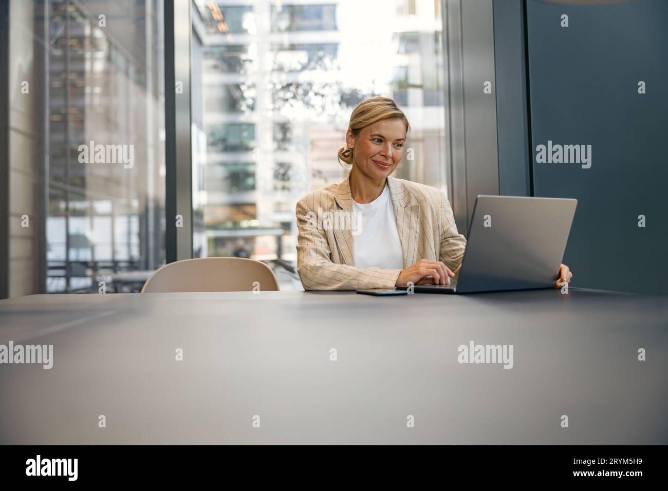 Female sales manager working on laptop while sitting the desk in modern ...