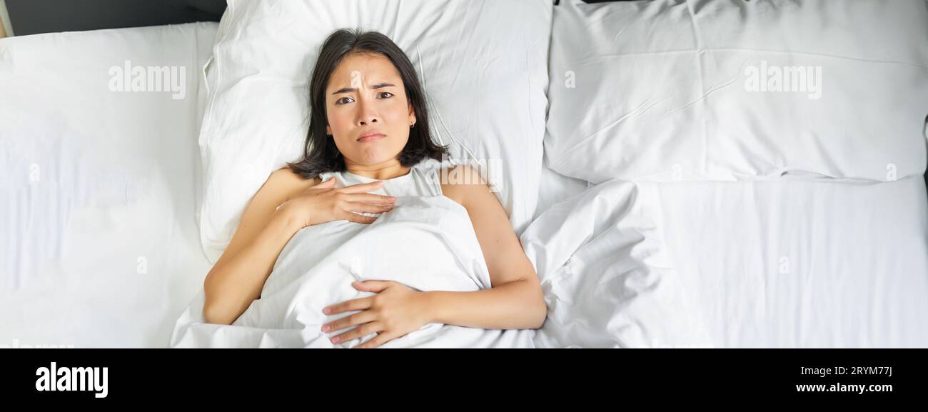 Portrait of sad young asian woman lying in bed, overthinking before ...