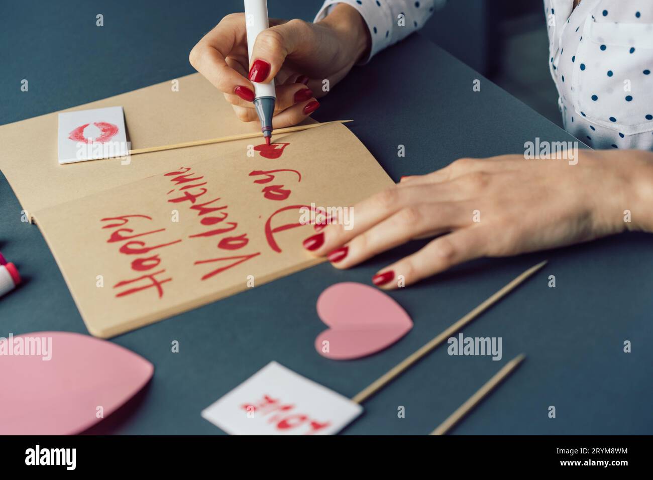 Woman writes in a sketch book with a felt-tip pen Happy Valentine's Day ...