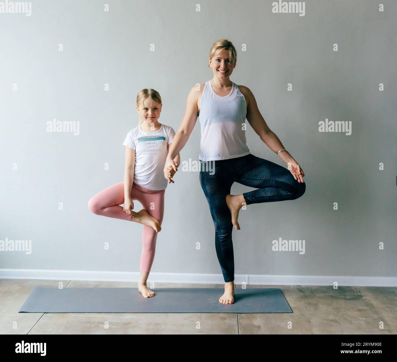 Mom and daughter in yoga balance pose in the gym Stock Photo - Alamy