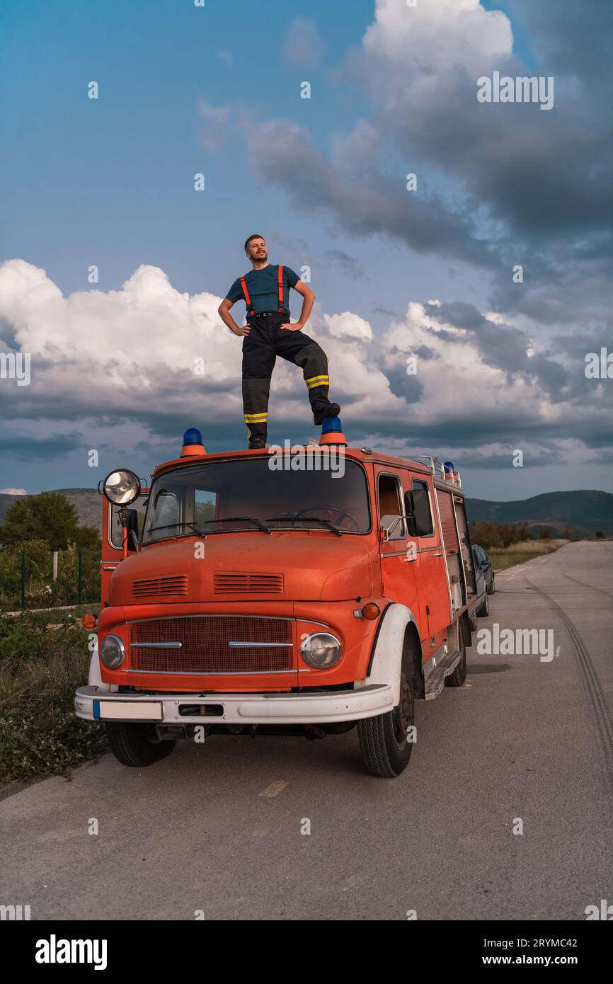The firefighter standing confidently on the fire truck, ready to ...