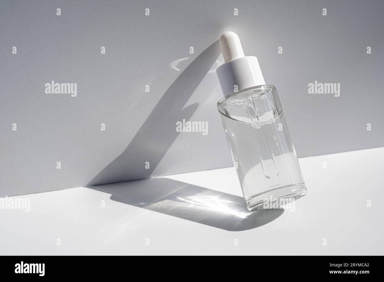 A white transparent bottle with serum in the rays of the sun Stock ...