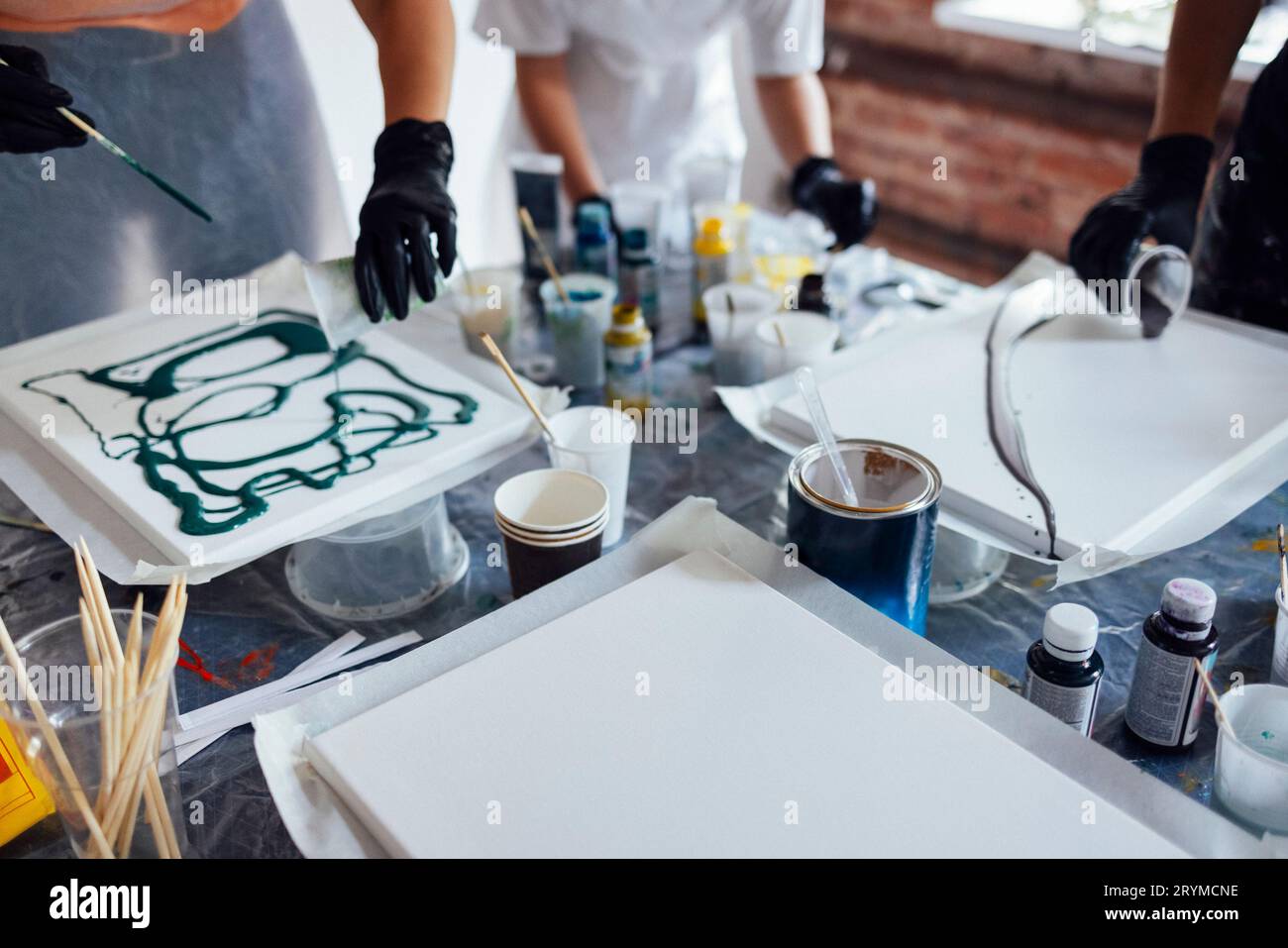 Master class on an Acrylic Fluid Pouring. Young women paint with liquid ...