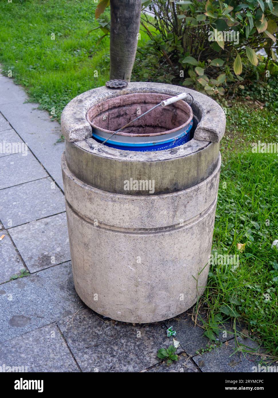 Garbage bin in the park. An iron bucket in a concrete urn ...
