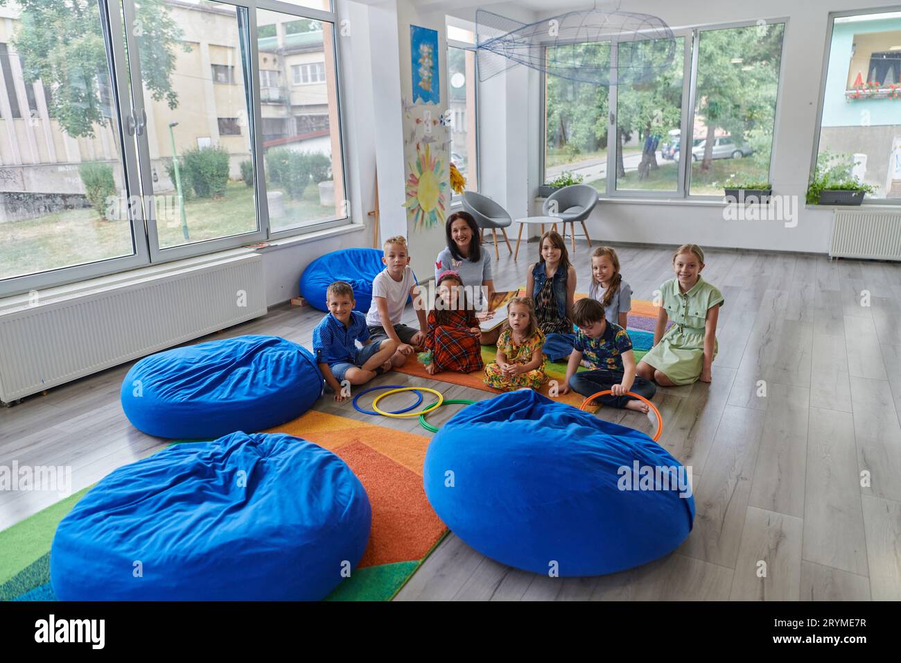 A happy female teacher sitting and playing hand games with a group of ...