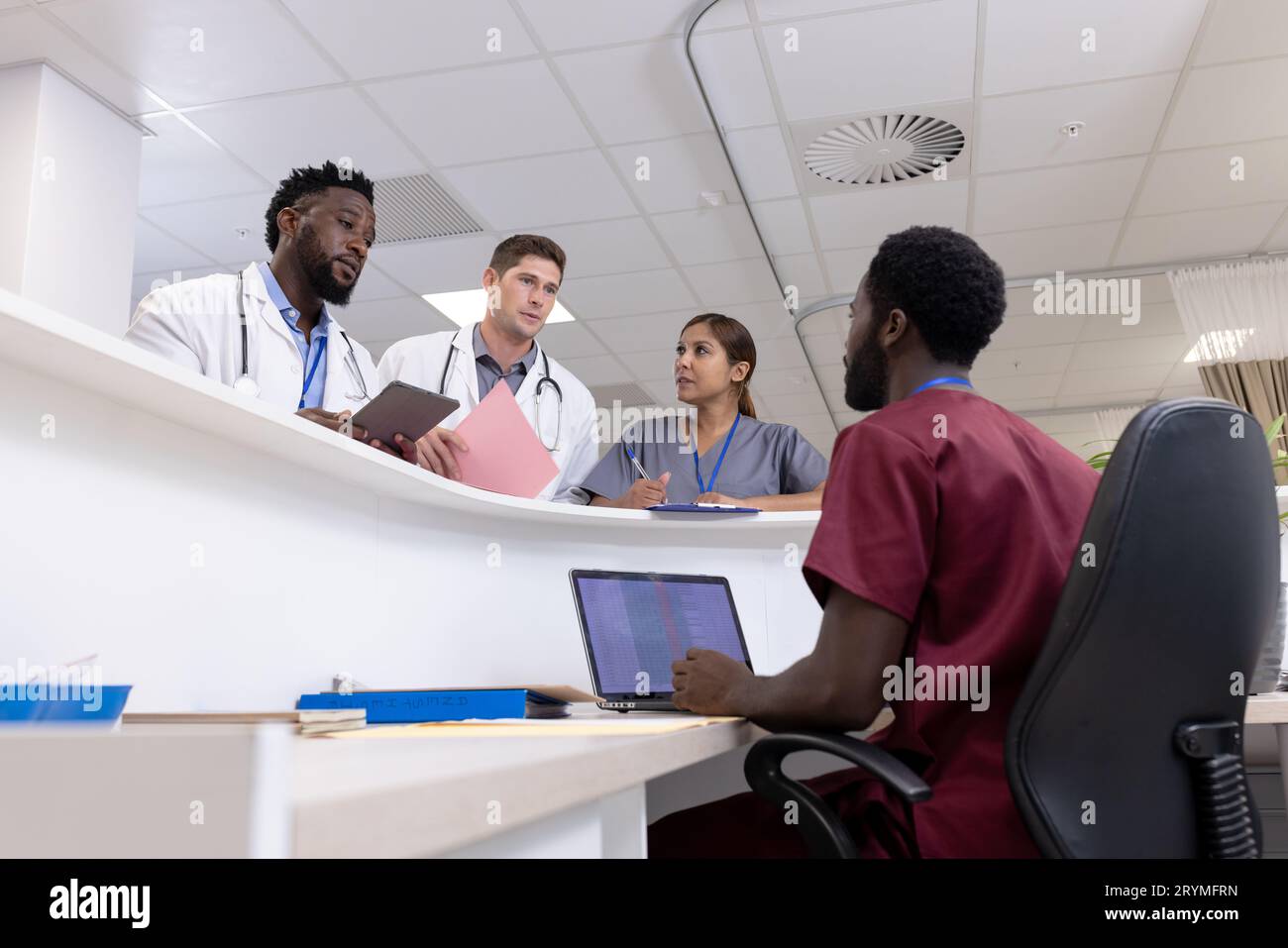 Busy diverse doctors and medical staff talking at reception desk of ...