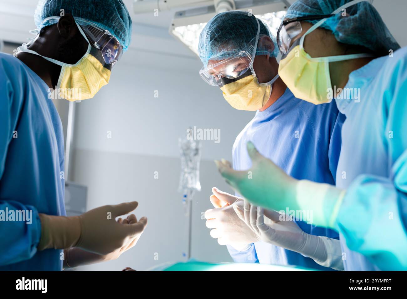 Diverse group of surgeons talking during surgery in operating theatre ...