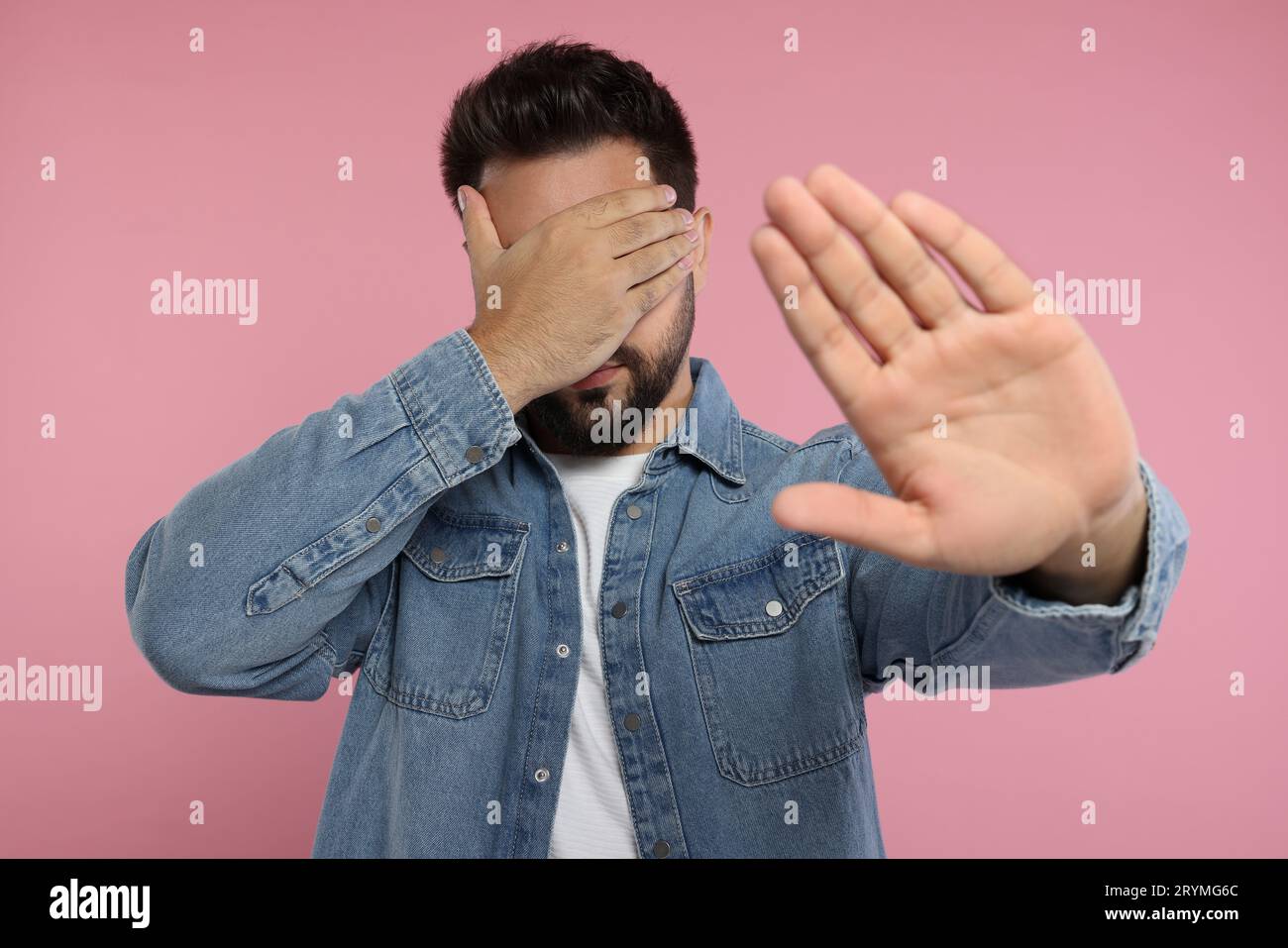Embarrassed man covering face with hand on pink background Stock Photo ...