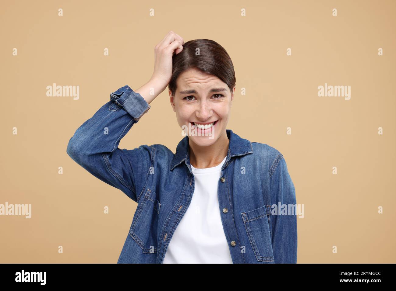 Portrait of embarrassed young woman on beige background Stock Photo - Alamy