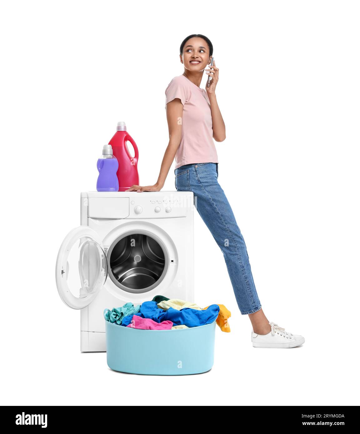 Beautiful woman talking on phone near washing machine with laundry against white background ...
