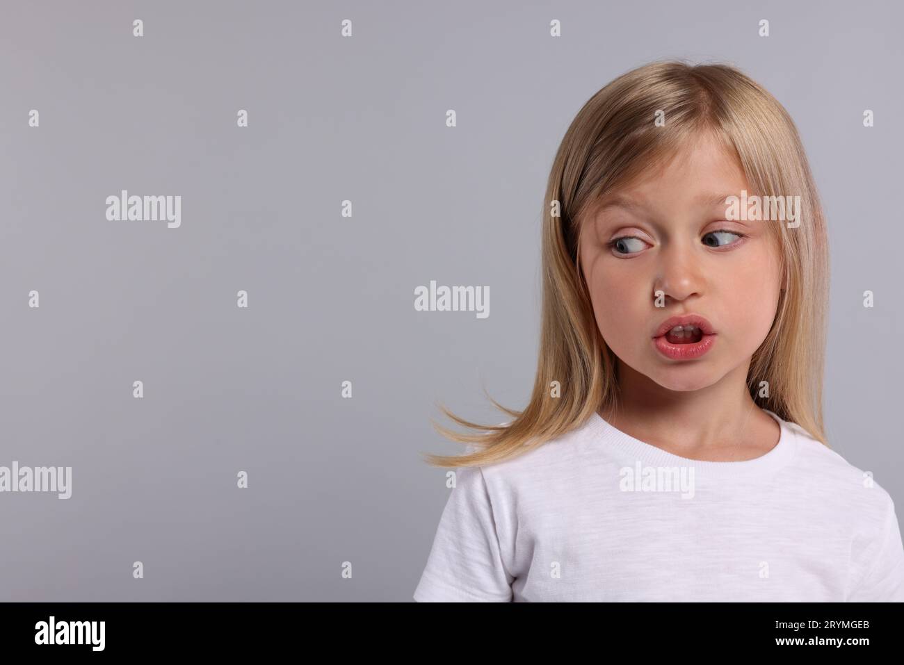 Embarrassed little girl on grey background. Space for text Stock Photo ...