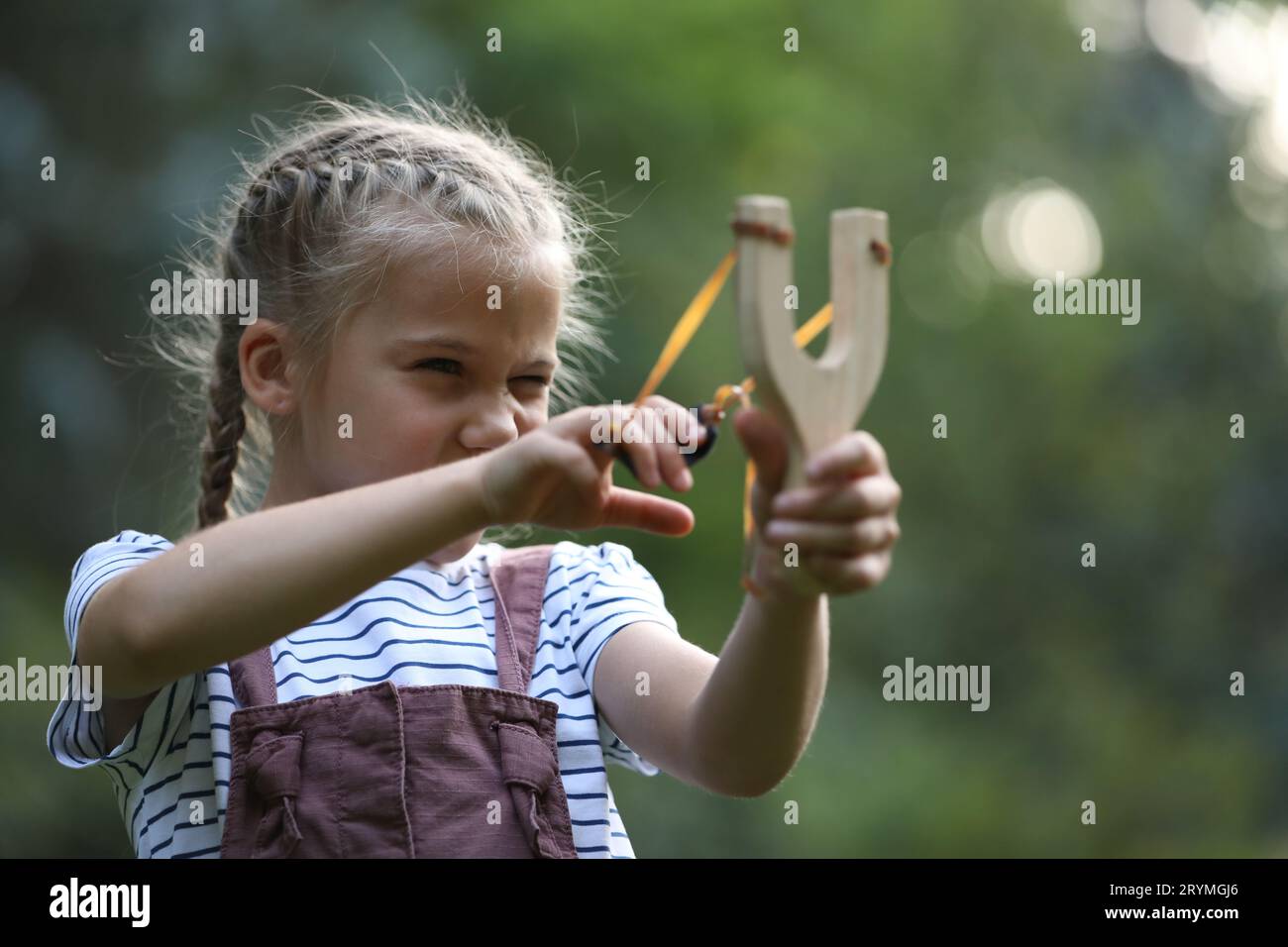 Little girl playing with slingshot in park Stock Photo - Alamy