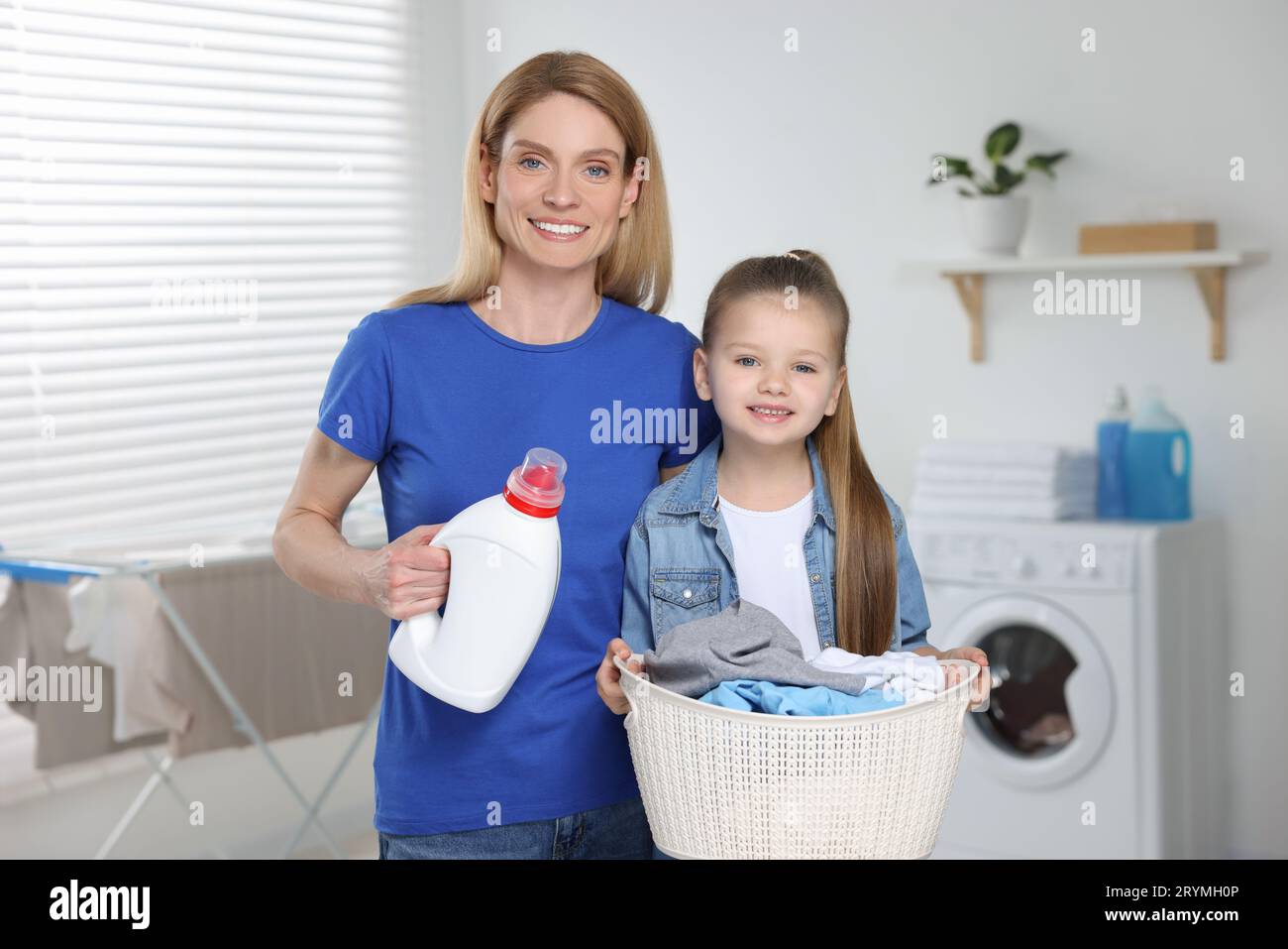 Mother and daughter holding basket with dirty clothes and fabric ...