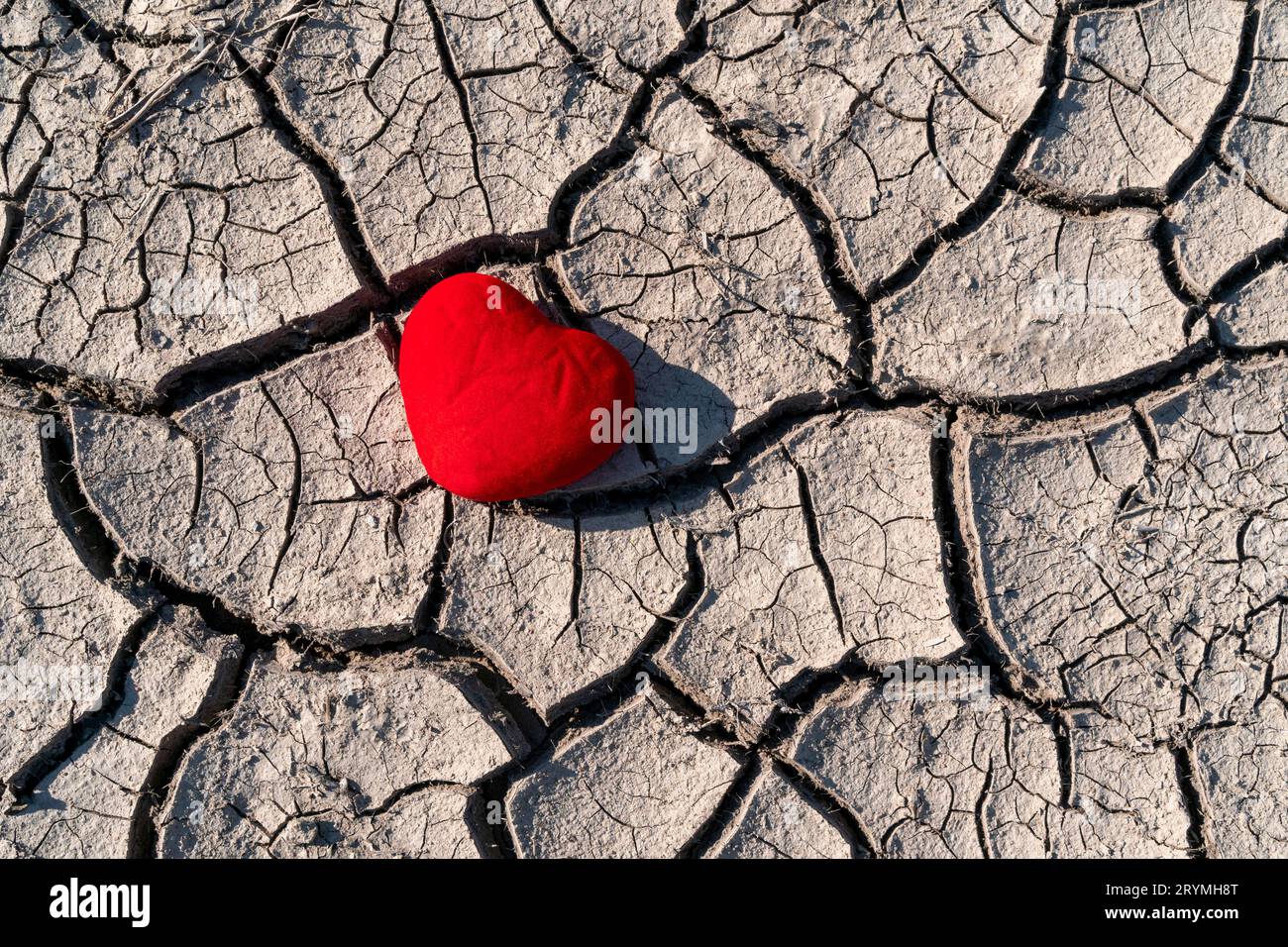 Red heart on soil drought cracked texture Stock Photo - Alamy
