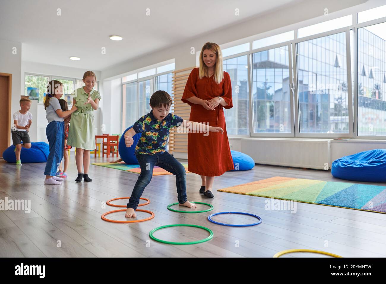 Small nursery school children with female teacher on floor indoors in ...