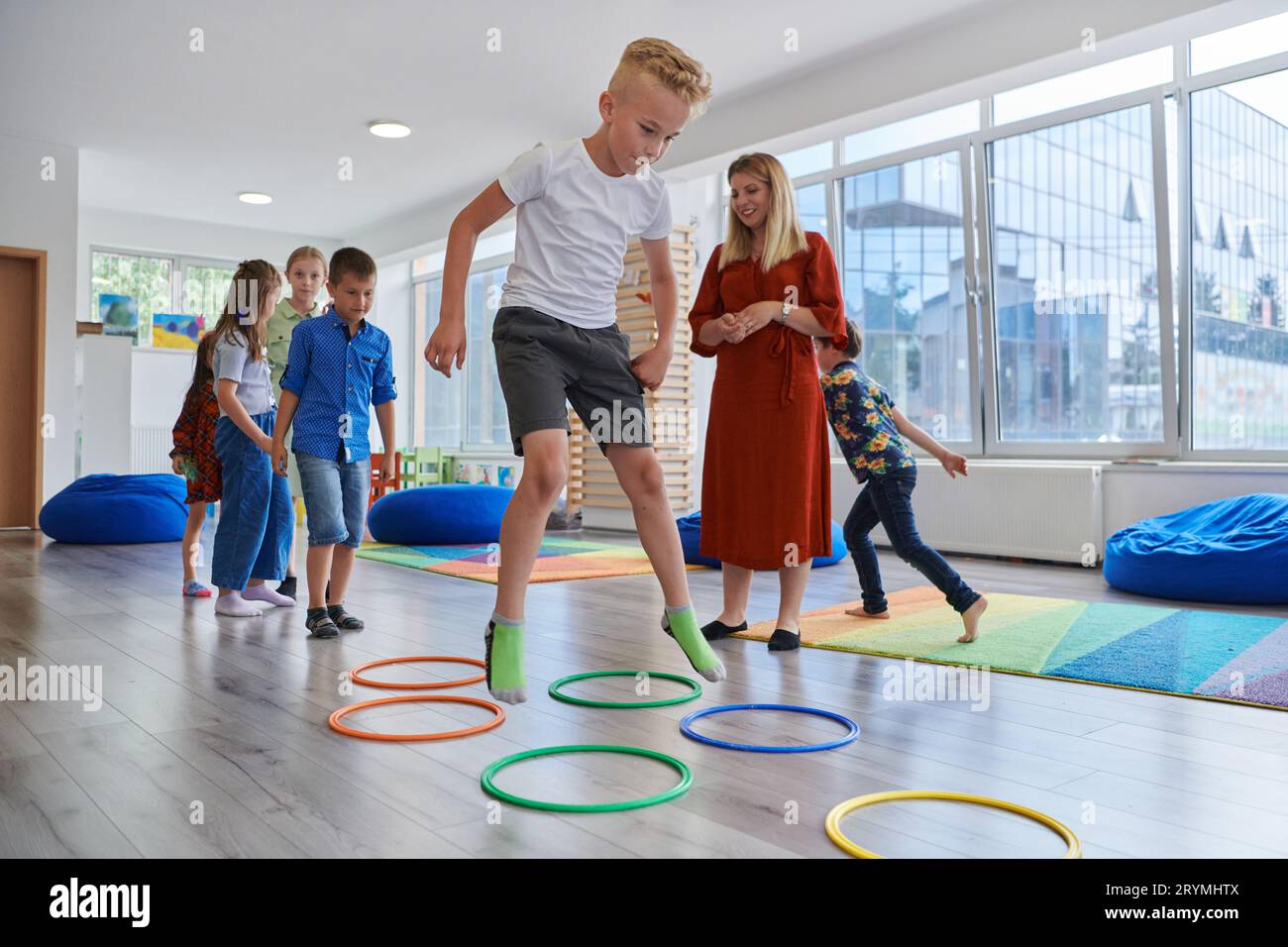 Small nursery school children with female teacher on floor indoors in ...