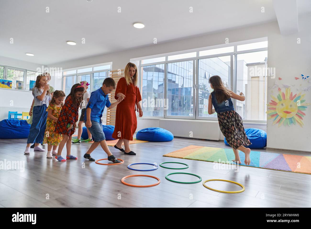 Small nursery school children with female teacher on floor indoors in ...