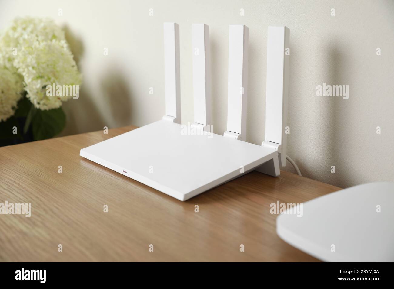 New modern Wi-Fi router on wooden table near white wall Stock Photo - Alamy