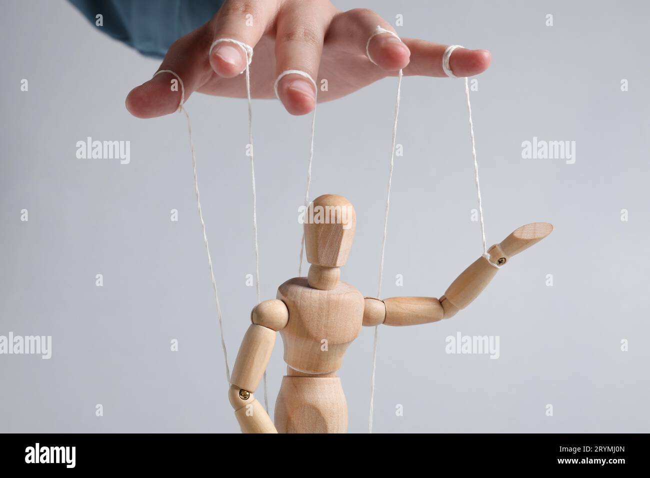 Woman pulling strings of puppet on light grey background, closeup Stock ...