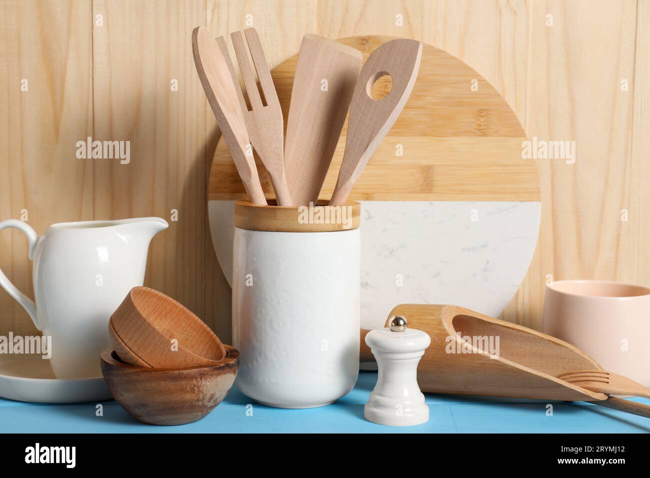 Set of different kitchen utensils on light blue table against wooden ...