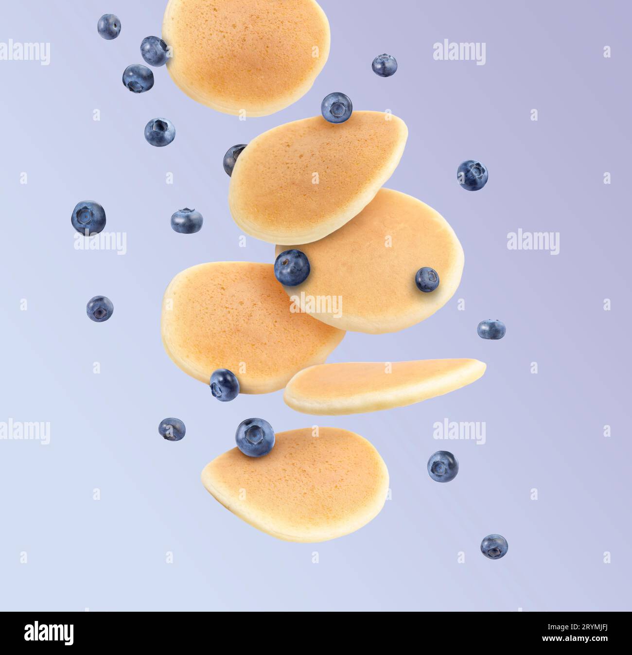 Many fresh pancakes and blueberries flying on pale blue background ...