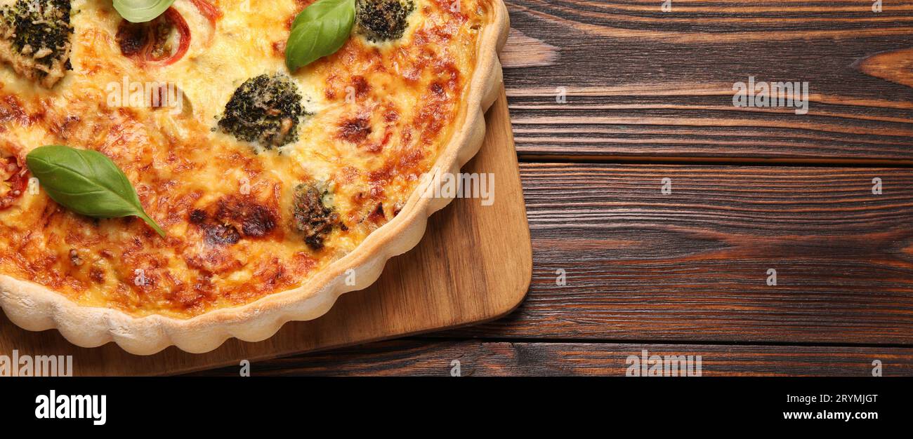 Delicious homemade vegetable quiche on wooden table, top view. Banner ...