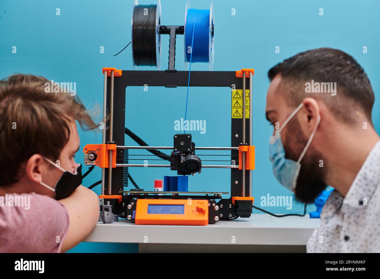A group of colleagues collaborate in a lab while testing a 3D printer ...