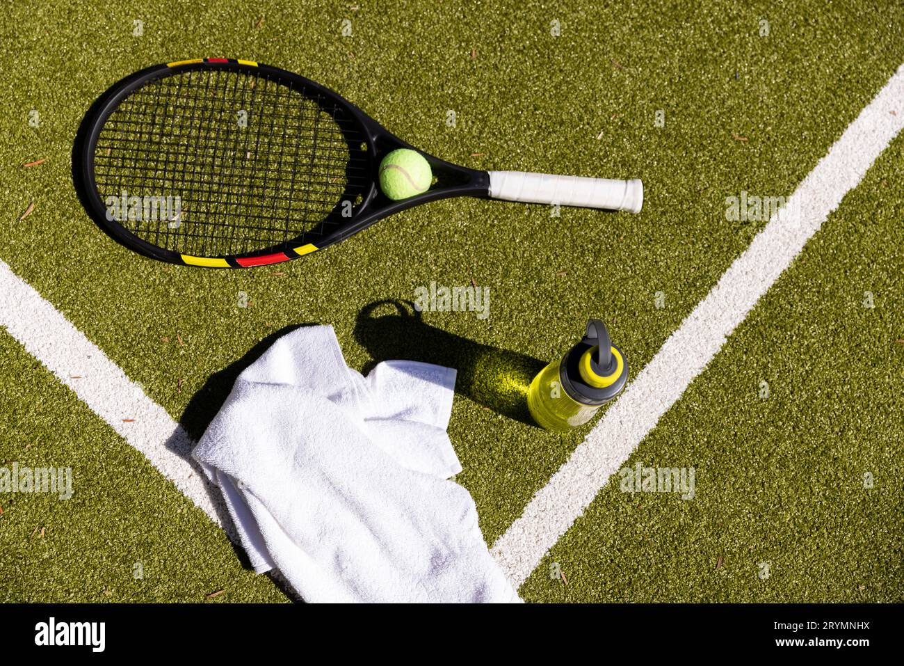 Tennis ball, racket, towel and water bottle lying on sunny outdoor ...