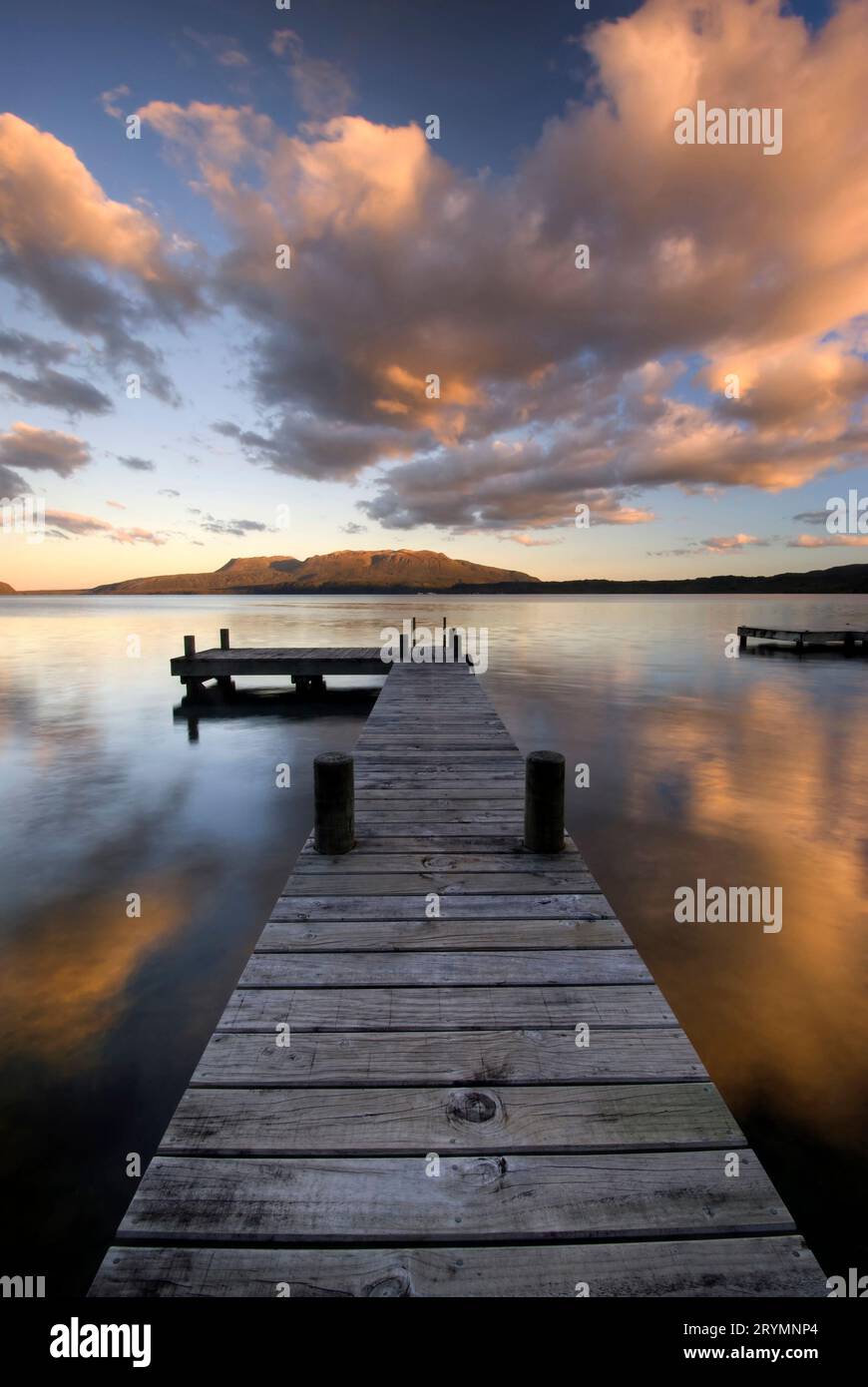 Suns last rays on Mt Tarawera with boat jetty in foreground. Sunset ...