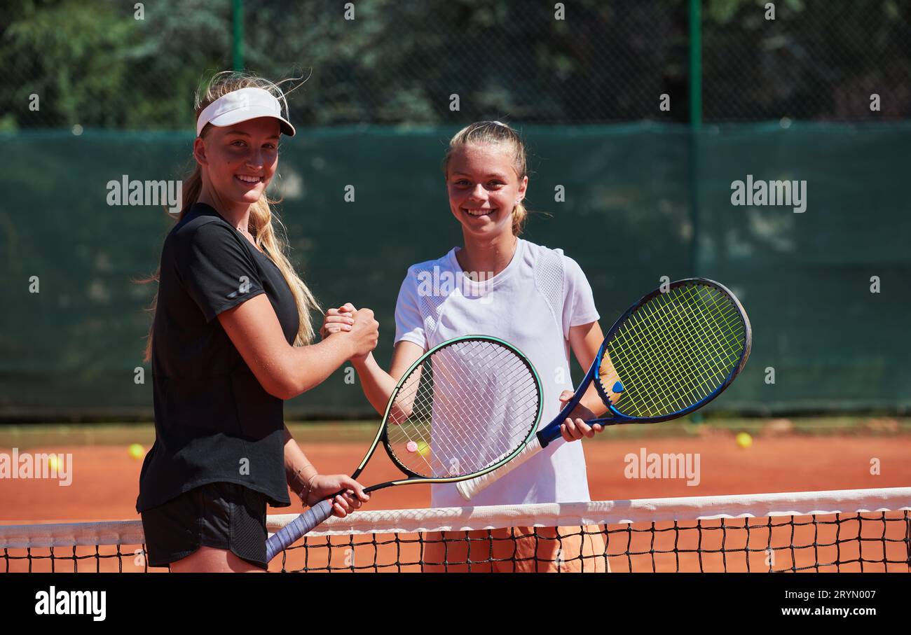 Two female tennis players shaking hands with smiles on a sunny day ...