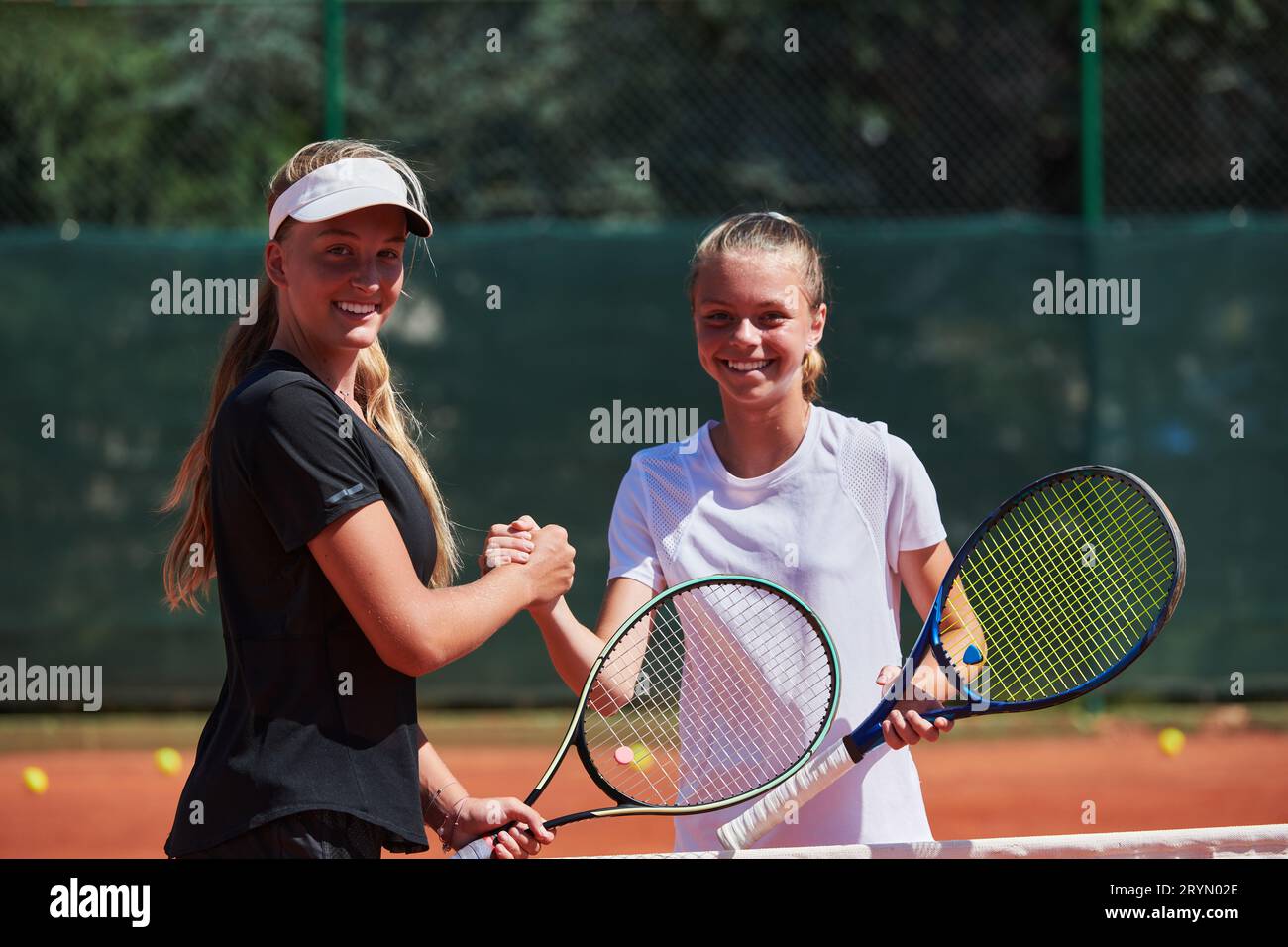 Two female tennis players shaking hands with smiles on a sunny day ...